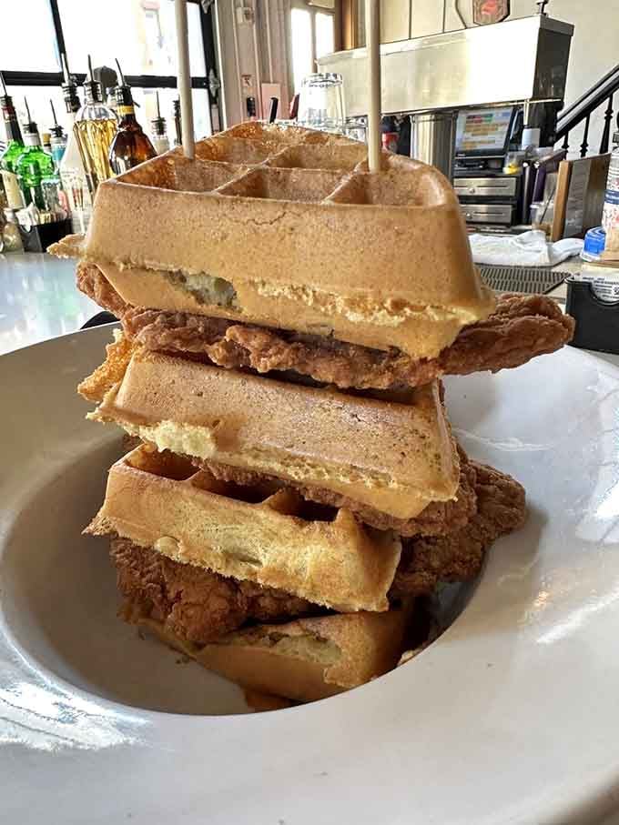 This towering stack of crispy fried chicken nestled between golden waffles defies gravity and common sense in the best way.