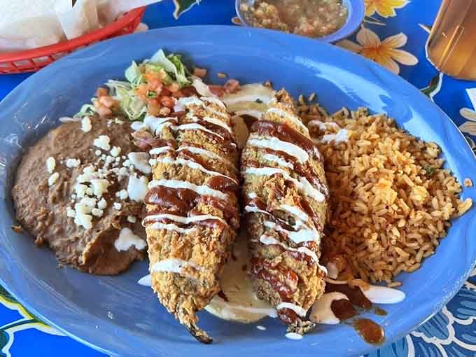 Those golden chile rellenos drizzled with sauce are basically edible sunshine on a vibrant blue plate.