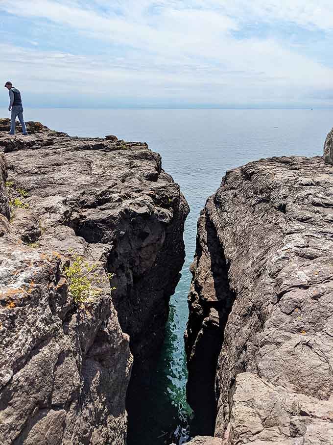 Ancient volcanic rock formations create dramatic crevices where Lake Superior shows off its stunning turquoise depths below.