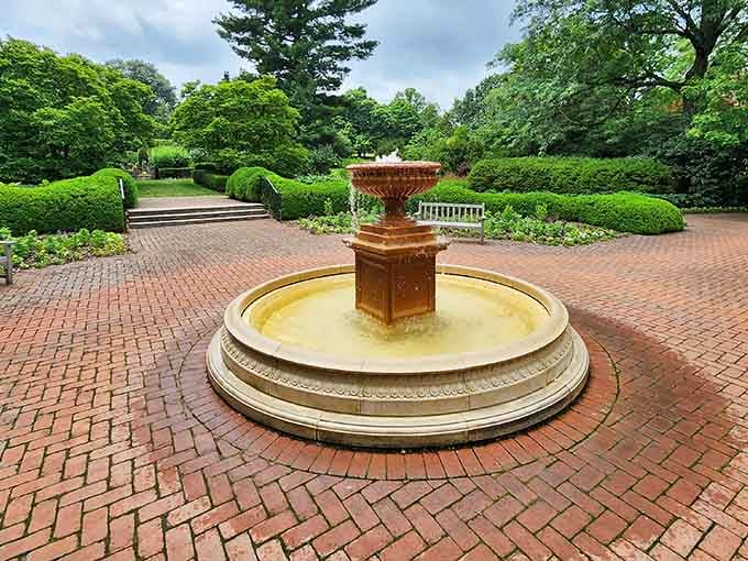 The central fountain anchors brick pathways where symmetry meets serenity in perfect horticultural harmony every single day.