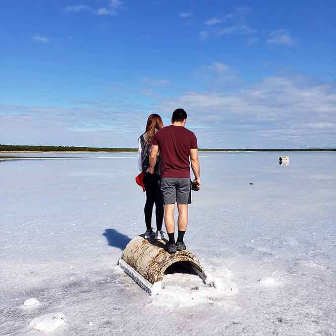 Two visitors contemplate the surreal beauty while standing on what appears to be frozen tundra in blazing heat.