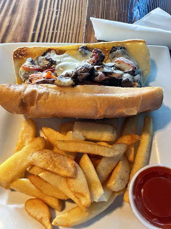 This Philly cheesesteak towers over its fries like a delicious skyscraper of melted cheese, steak, and pure satisfaction.