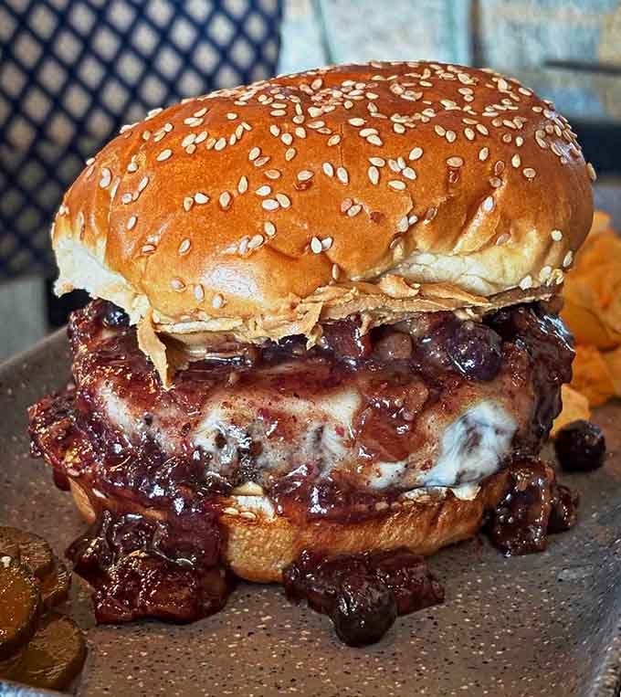 A burger topped with blueberry bacon jam on a sesame bun proves sweet and savory belong together forever.