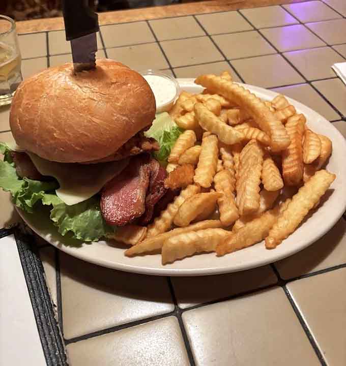That burger sits tall and proud, surrounded by crispy fries that could make a grown person weep with joy.