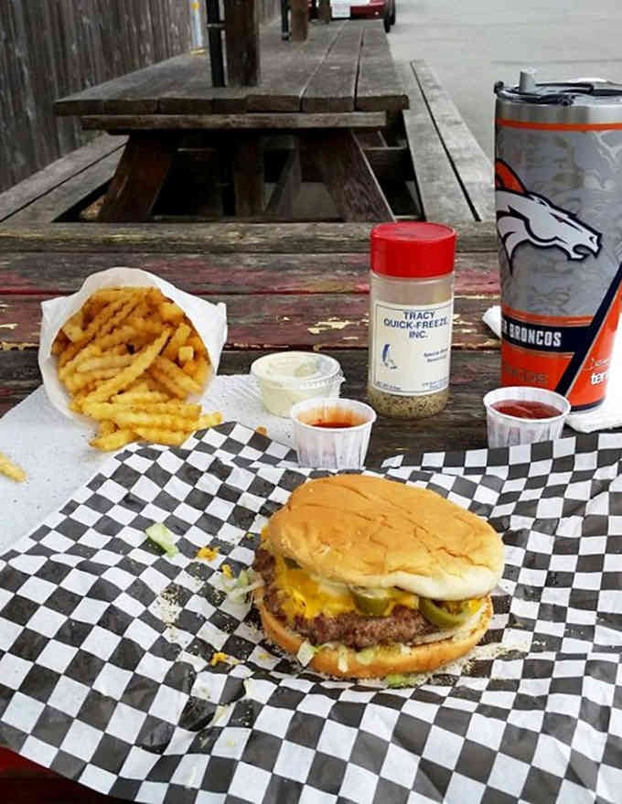 Classic checkered paper, golden fries, and a juicy burger on weathered wood, this is outdoor dining done absolutely right.