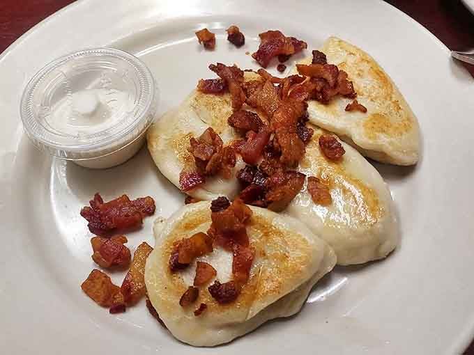 Golden pierogi topped with bacon bits that could make a vegetarian seriously reconsider their life choices.