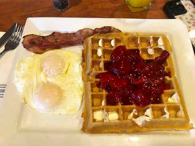 Golden waffles topped with strawberry compote, proving that breakfast dessert is absolutely a legitimate category.