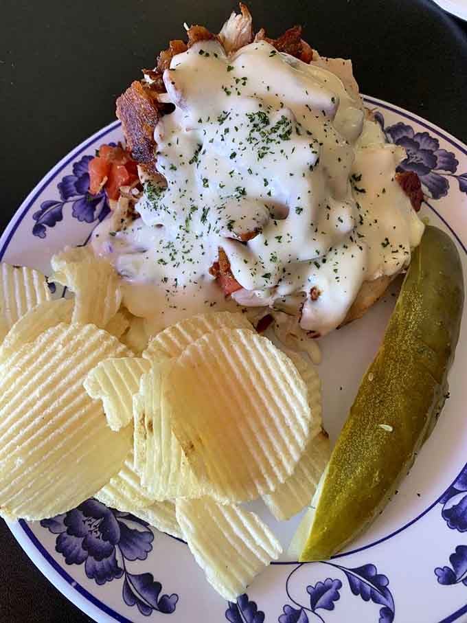 The Hot Brown Sandwich arrives smothered in creamy sauce like comfort food wearing its Sunday best.