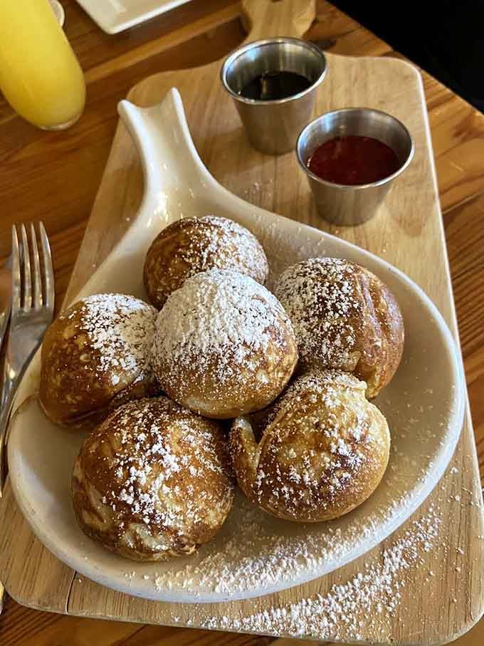 Danish pancake balls dusted with powdered sugar and served with syrups, making you question why all pancakes aren't spherical.