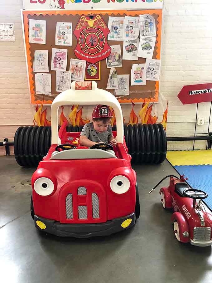 Future firefighters start their training early with this adorable kiddie ride, complete with helmet and serious determination on display.