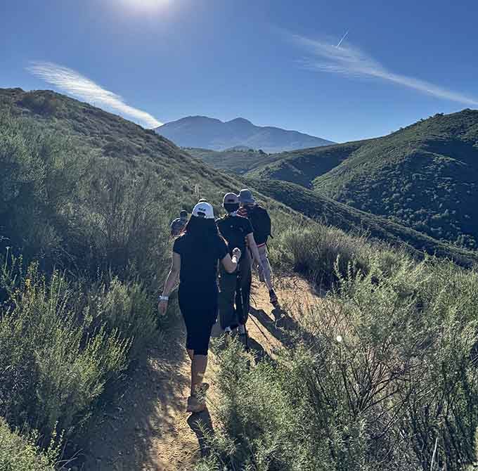 The trail stretches ahead through chaparral country, where the landscape whispers that waterfalls are worth every sweaty step forward.