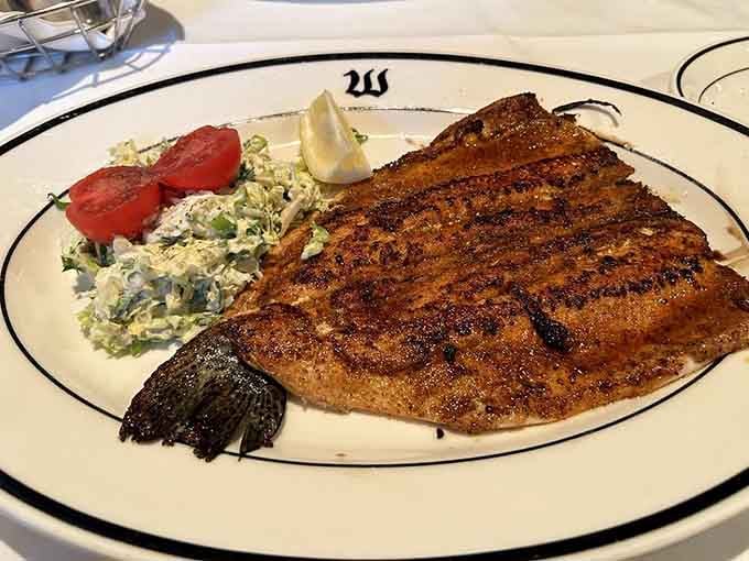 The Cajun trout arrives beautifully seasoned and perfectly grilled, proving Weber's mastery extends beyond red meat alone.