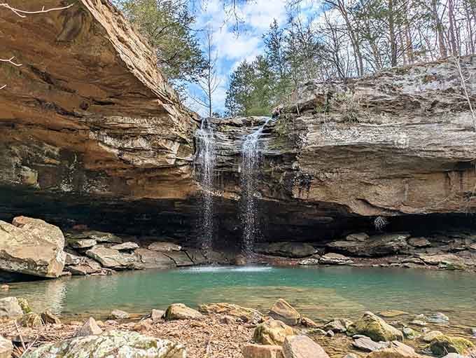 Twin waterfalls spill over golden sandstone into an emerald pool that belongs in a fantasy novel, not southern Illinois.