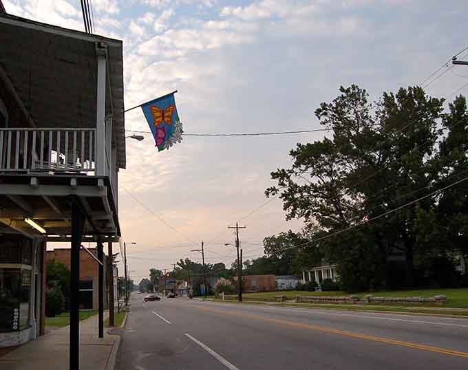 A colorful flag dances in the breeze above quiet streets as evening light softens everything.
