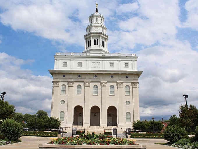 The Nauvoo Temple rises like a brilliant white beacon, its golden statue gleaming against clouds that can't compete for attention.
