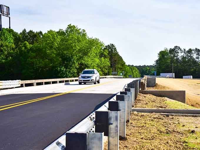 Fresh asphalt stretches toward the tree line, proving that even newly paved roads can lead to timeless natural wonders.