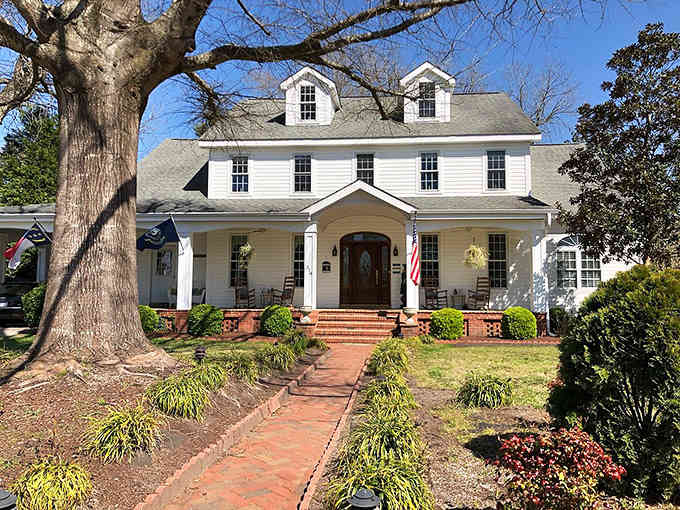 That oak tree has seen more history than most textbooks, standing guard over this pristine colonial home's brick walkway.