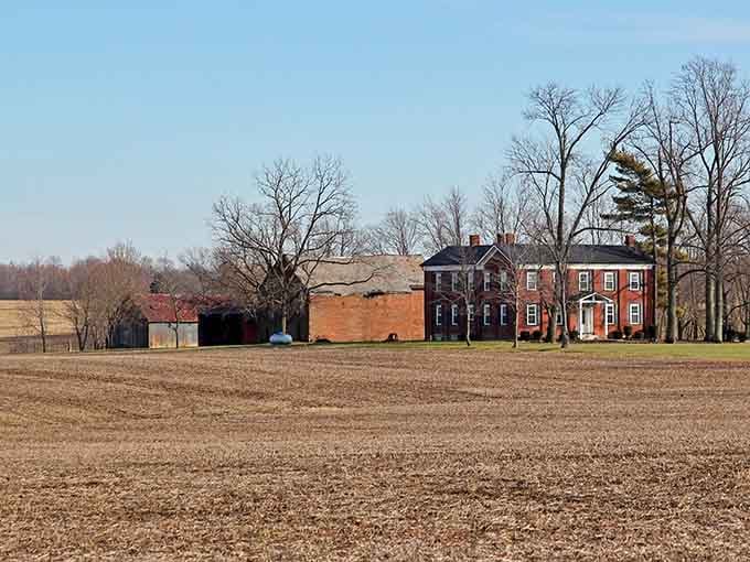 Historic brick farmhouse stands surrounded by open fields like a sentinel watching over the land for generations.