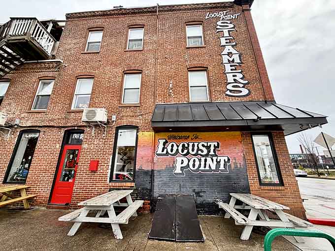 The welcoming red door and outdoor picnic tables signal casual dining where crabs and conversation flow freely.