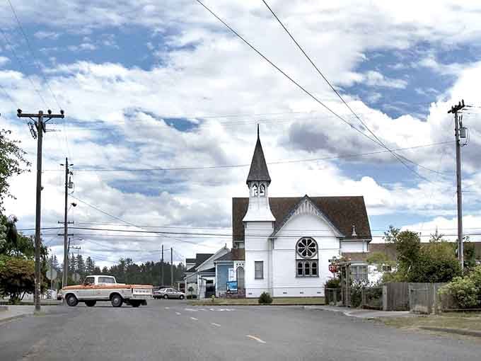 That classic white church steeple rises against dramatic clouds, anchoring a town where Sunday still means something special.