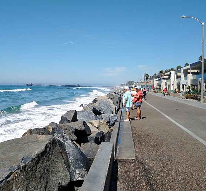 The Strand stretches along the coastline where waves crash against rocks and walkers enjoy endless Pacific Ocean views.