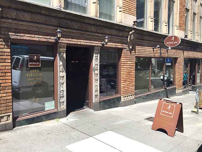 Those horizontal brick lines and street-level windows frame a bustling scene of pizza lovers getting their fix right.