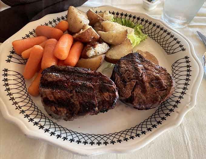 Two beautiful filet mignons flanked by carrots and potatoes on decorative china, because presentation still matters in classic dining.