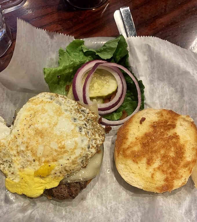 A fried egg crowns this burger like edible royalty, because why stop at just one protein source?