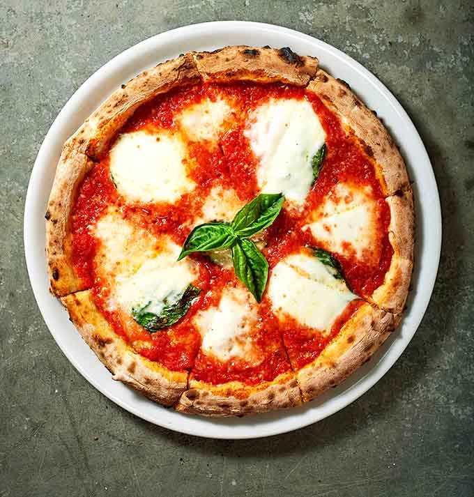 Fresh mozzarella pools and basil leaves on a perfectly charred crust create the kind of pizza that haunts your dreams.