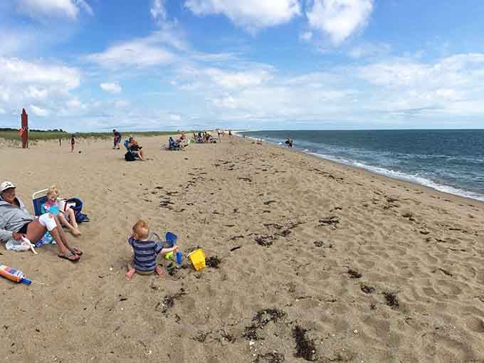Families claiming their perfect spots on this expansive beach, building sandcastles and memories that'll outlast any sunburn they get.