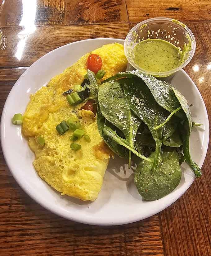 A fluffy omelet paired with fresh greens and that housemade green sauce creates breakfast perfection on a plate.