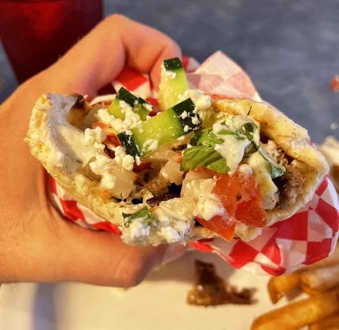 Behold the gyro in all its glory: tender meat, fresh veggies, and tzatziki that'll haunt your dreams forever.