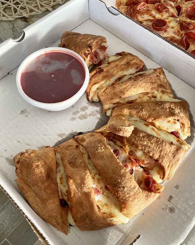That golden-brown stromboli is stuffed with cheese and goodness, served with marinara for dipping because life is good.