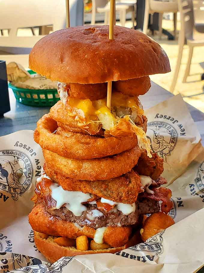 This towering burger construction defies gravity and good sense, stacked with onion rings and everything else that makes life worth living on a bun.