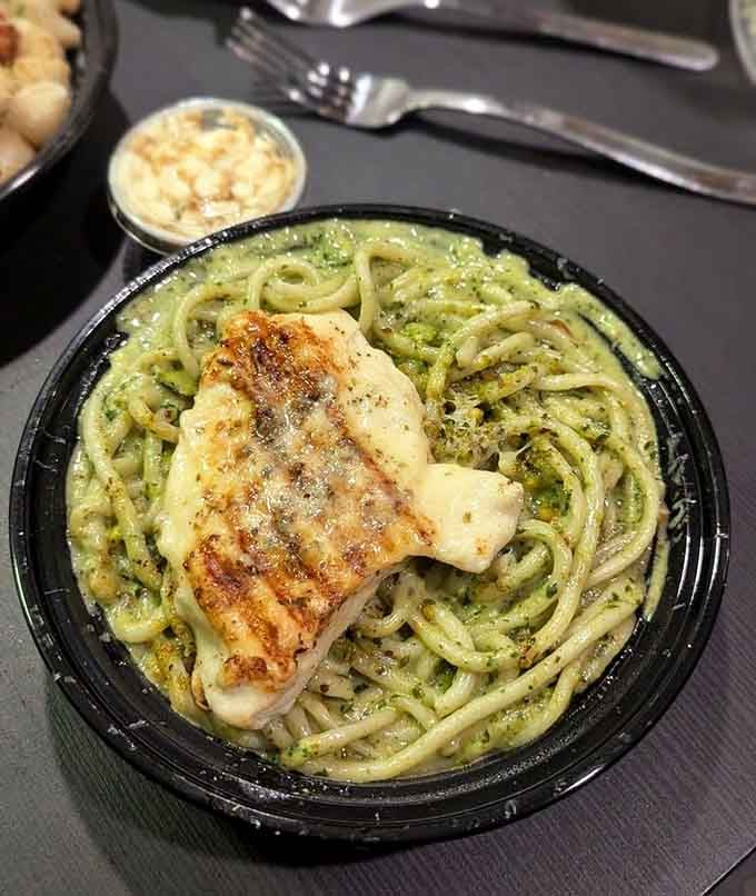 Grilled chicken crowning a nest of vibrant pesto bucatini looks like summer decided to become dinner.