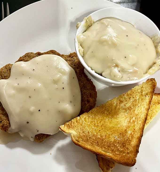 Country fried steak smothered in gravy with a side of grilled toast&mdash;breakfast done absolutely right.