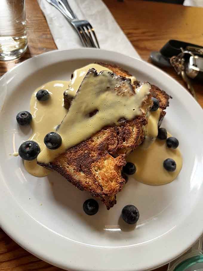 Baked French toast with blueberries and sauce that looks like liquid gold poured over carbohydrate heaven itself.