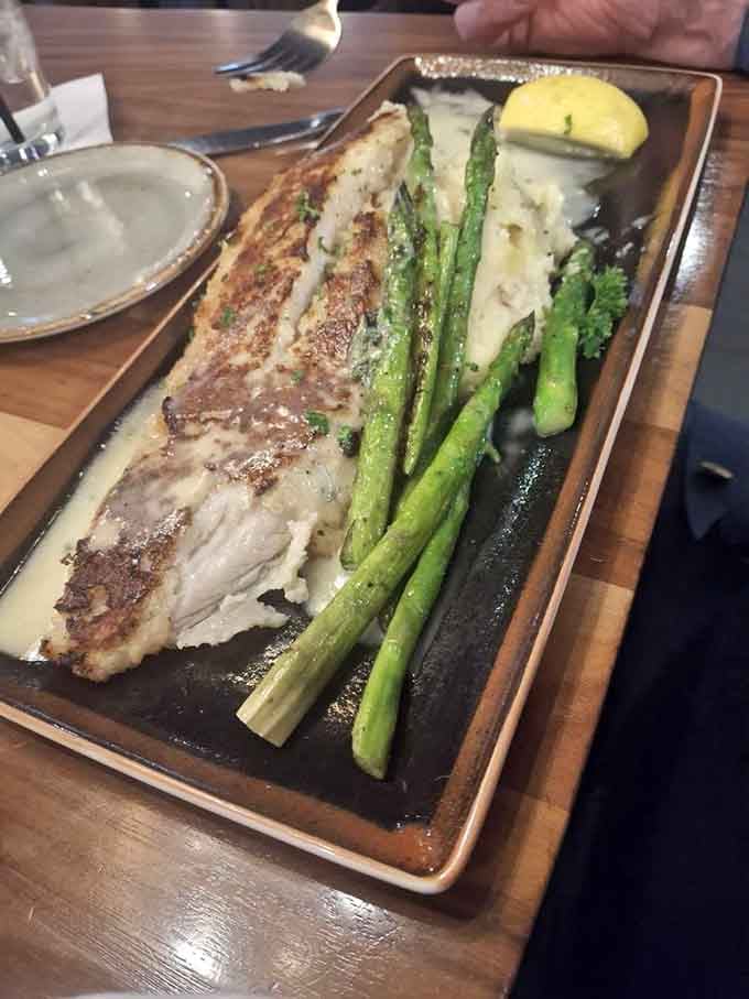 Pan-crusted walleye on a sizzling platter with asparagus and lemon, looking like it just stepped off a cooking show set.