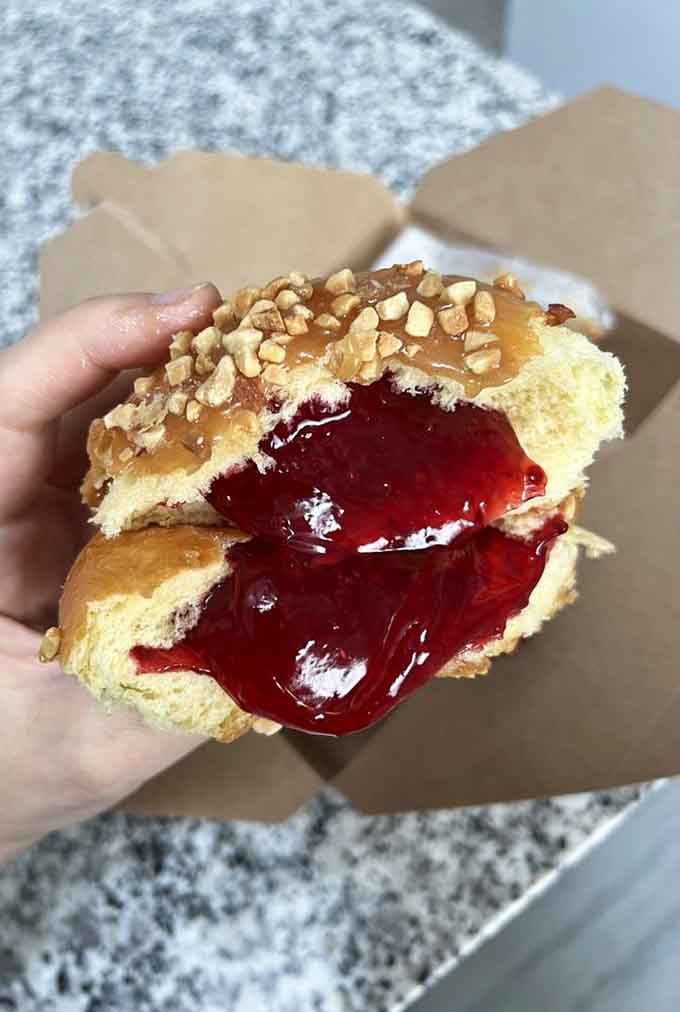 That ruby-red jelly filling bursting out is basically edible joy captured in a single, glorious moment of indulgence.