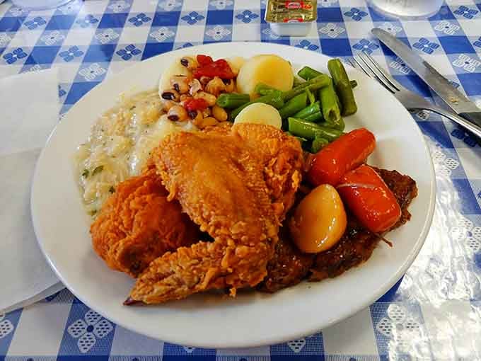 That crispy fried chicken sits atop mashed potatoes like a delicious throne, surrounded by colorful veggie subjects paying tribute.