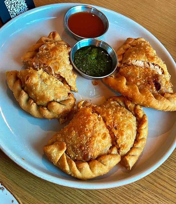Golden empanadas served with vibrant sauces that make you wonder why all food doesn't come this beautifully presented.