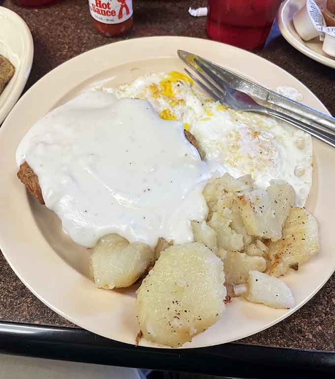 Country fried steak smothered in gravy with fried potatoes: this is what breakfast dreams are made of, folks.