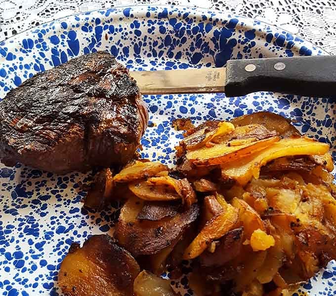 Filet mignon meeting those golden German potatoes on speckled blue pottery is pure comfort food poetry.