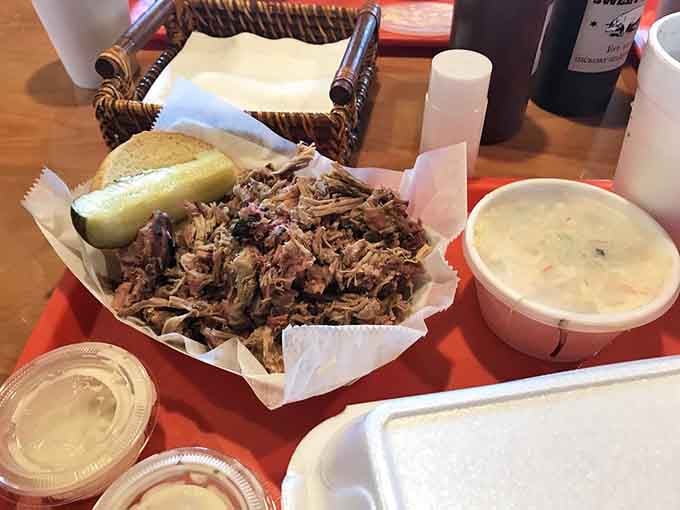Pulled pork piled high enough to require architectural support, served with pickles for structural integrity.