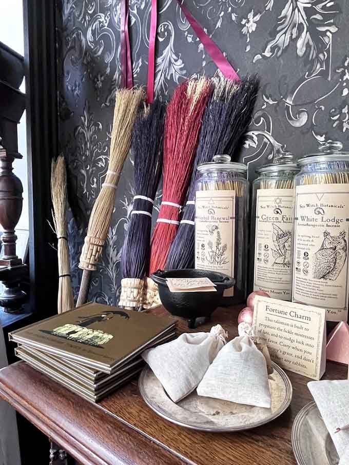 Traditional besom brooms hanging beside ritual candles, ready for sweeping both floors and negative energy with equal efficiency.