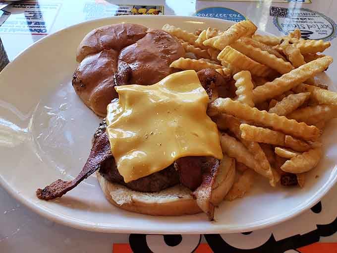 That burger wears its cheese like a crown, accompanied by fries and onion rings for maximum indulgence.