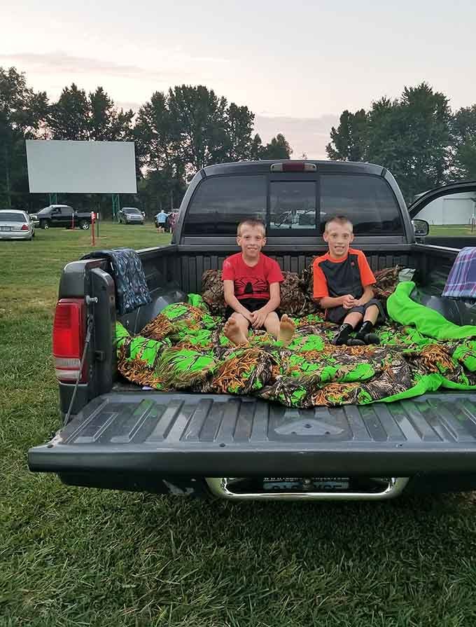 Kids getting cozy in the truck bed, living their best drive-in life with blankets and pure excitement.
