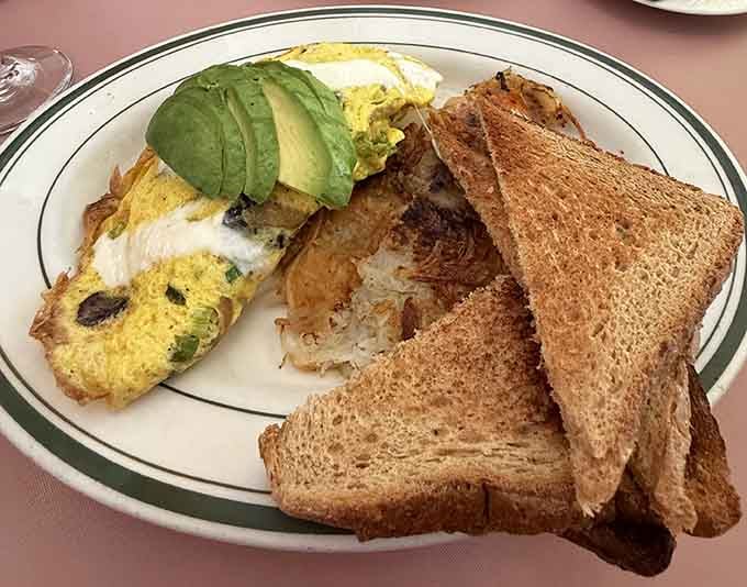 This omelet arrives fluffy and generous, topped with fresh avocado like edible sunshine on your plate.