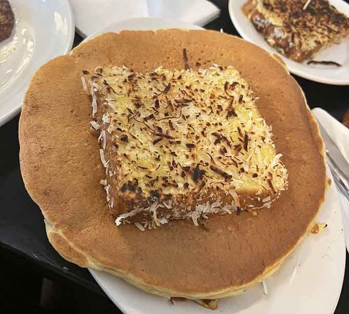 Pancakes so fluffy they practically float off the plate, topped with what appears to be toasted coconut perfection.