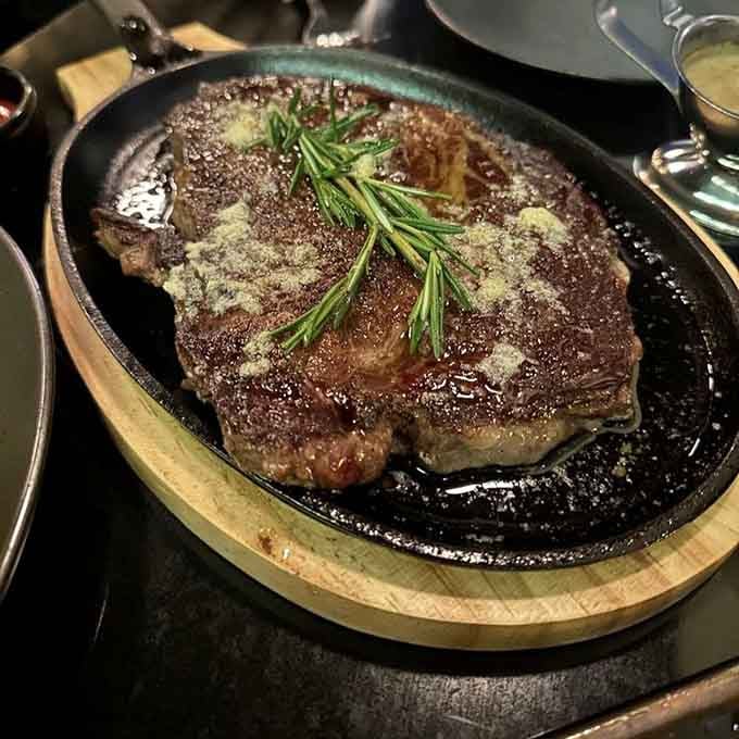 That sizzling Wagyu steak arrives on a hot skillet with rosemary garnish, looking like it just stepped off a food magazine cover.
